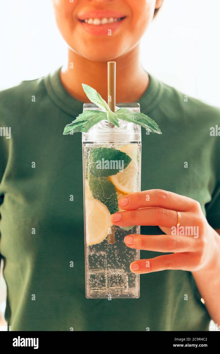 Unrecognizable smiling female standing with bottle of detox drink with ...