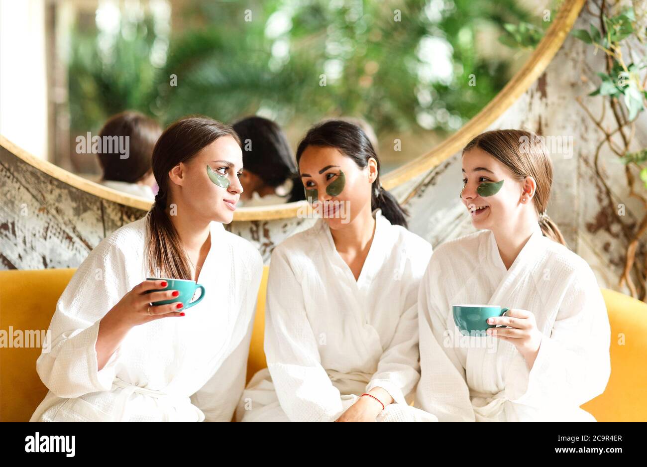 Group of friendly women in white bathrobes and eye patches sitting in ...