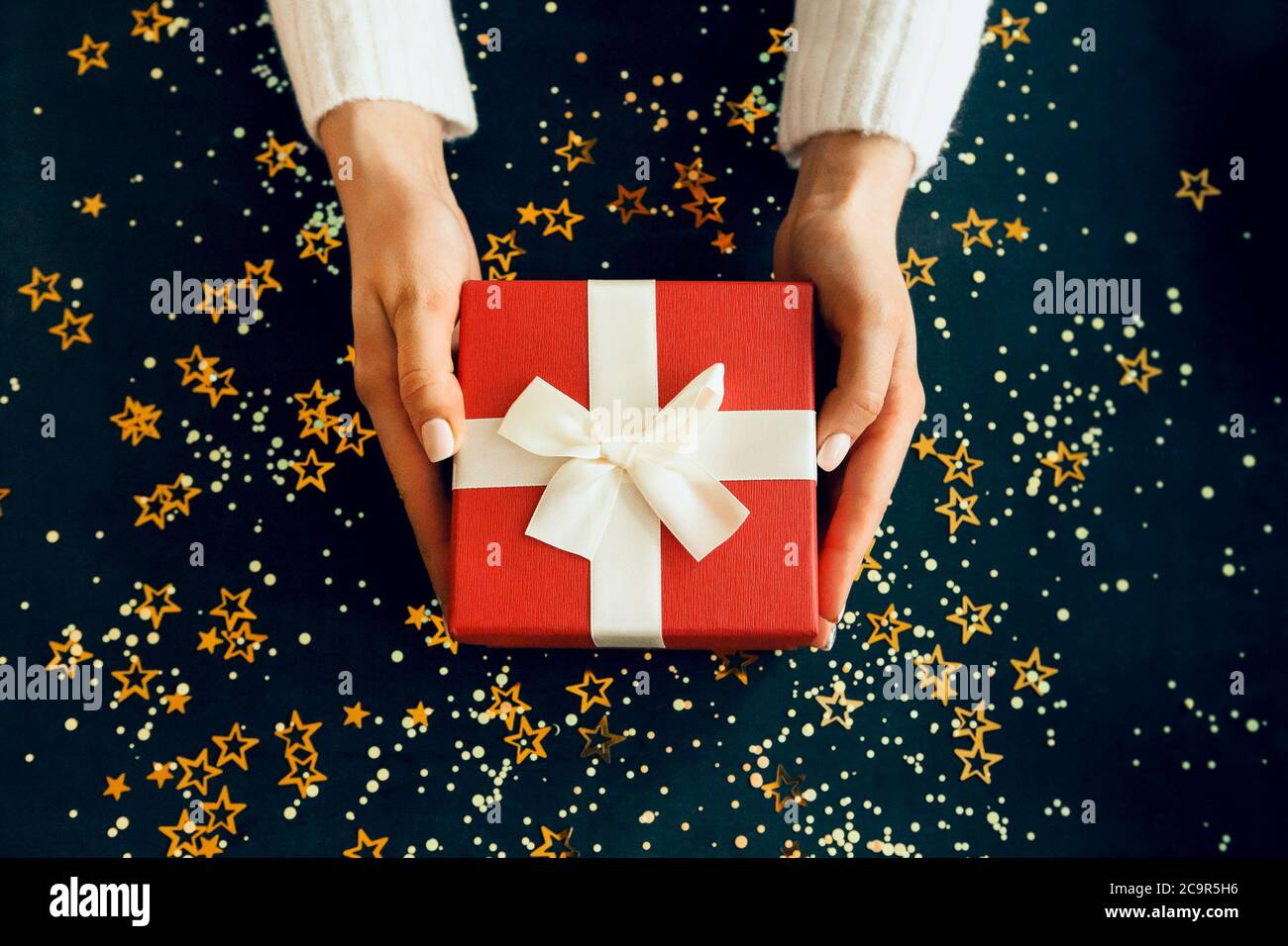 From above of anonymous female with wrapped present decorated with red ...