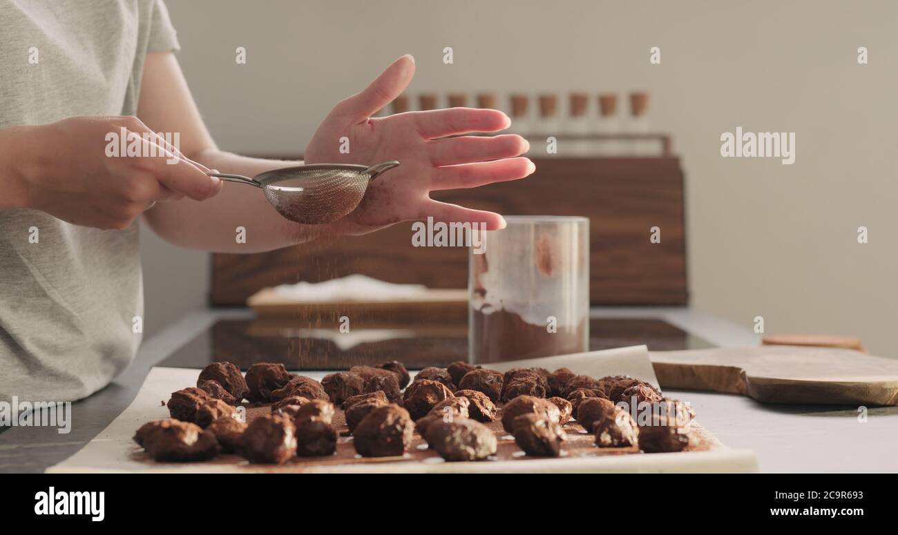 young woman sprinkle cocoa powder on chocolate truffles Stock Photo - Alamy