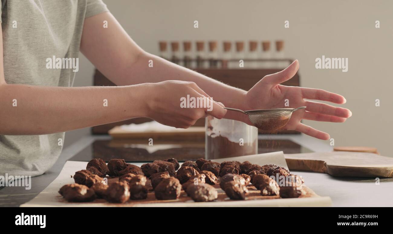 young woman sprinkle cocoa powder on chocolate truffles Stock Photo - Alamy