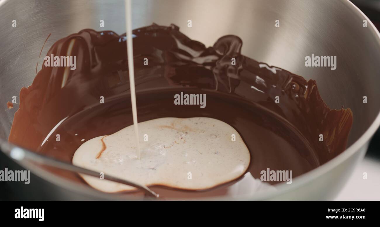 adding cream into melted chocolate in steel bowl Stock Photo - Alamy