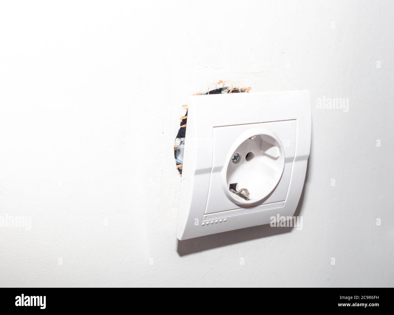 Broken electric socket torn from white wall. Fixing loose electrical ...