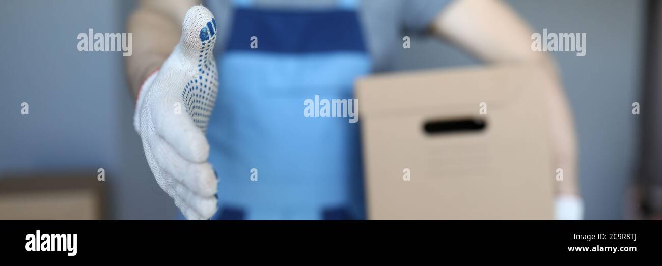 Loader man with box stands holding out his hand Stock Photo - Alamy