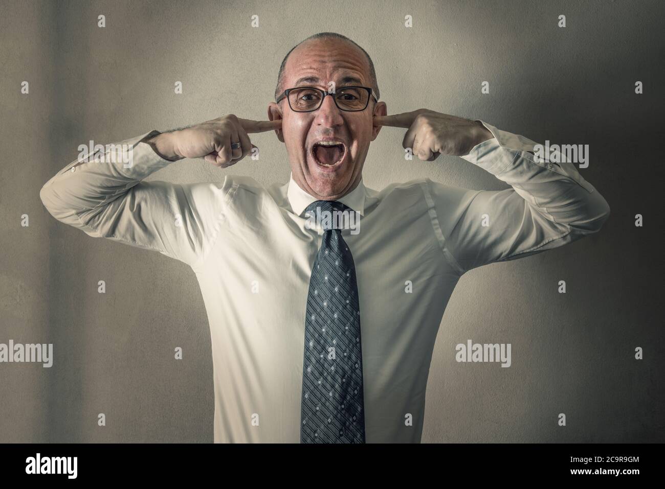 a Stressed manager screaming with his fingers in his ears Stock Photo ...