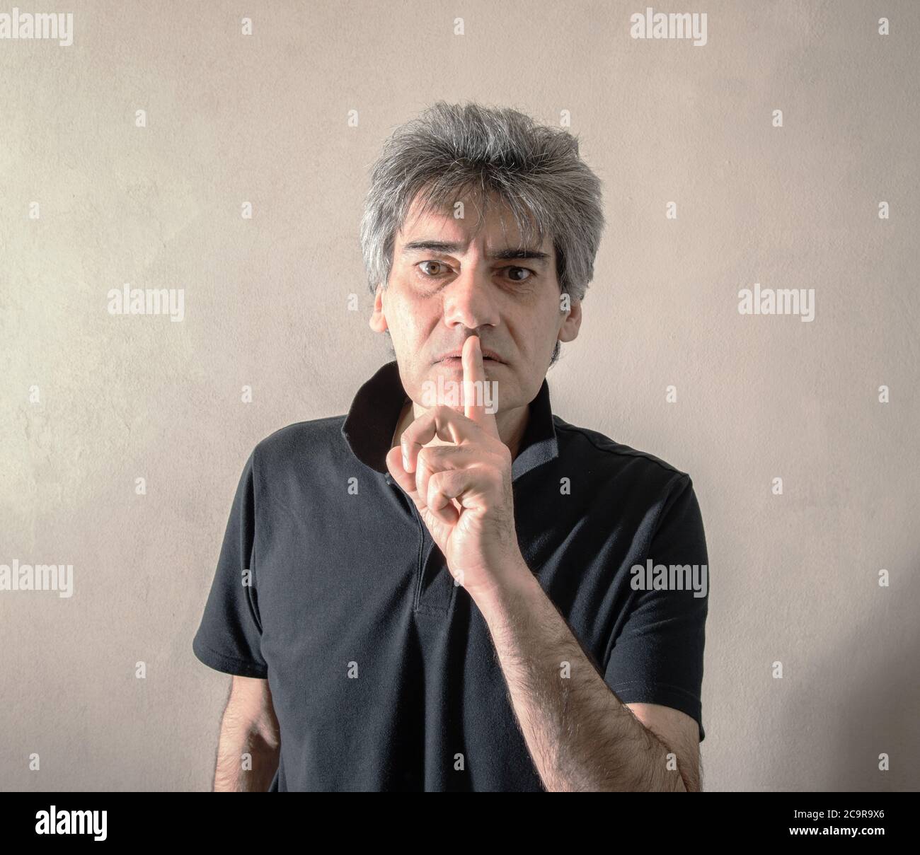 a Man doing the gesture of silencing Stock Photo - Alamy