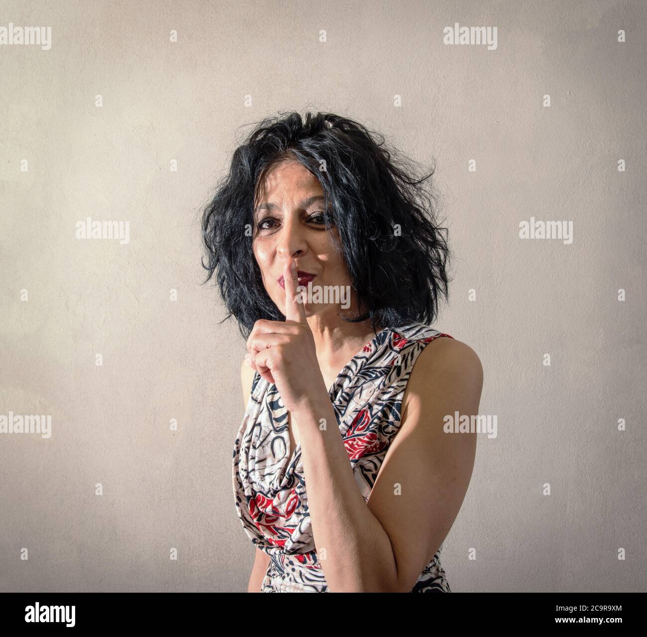 a nice woman doing the gesture of silencing Stock Photo - Alamy