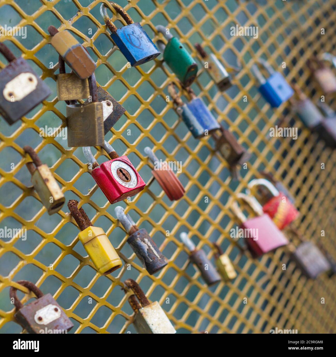 colorful locks hanging from yellow chain fence Stock Photo - Alamy