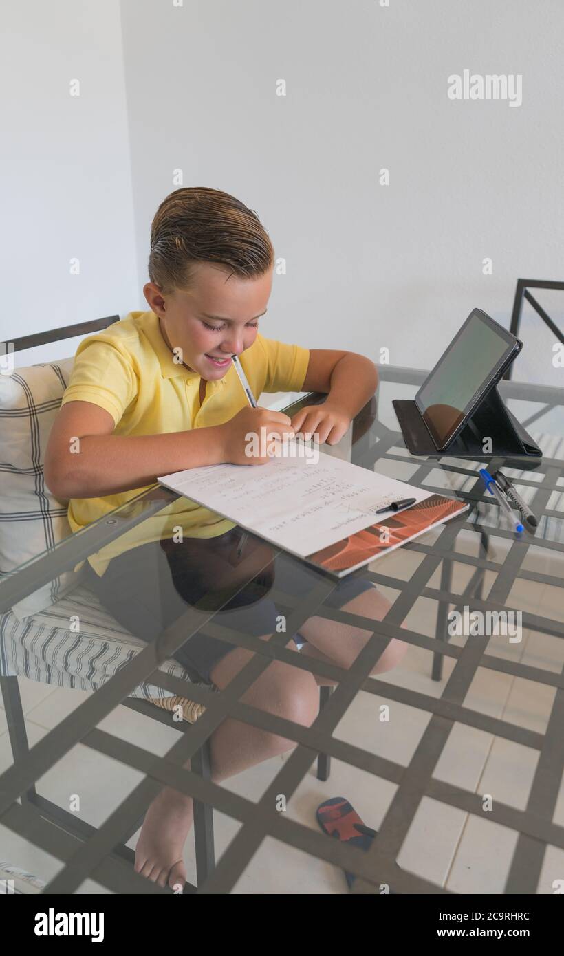 Young boy doing homework at home on dining room table concentrating and ...