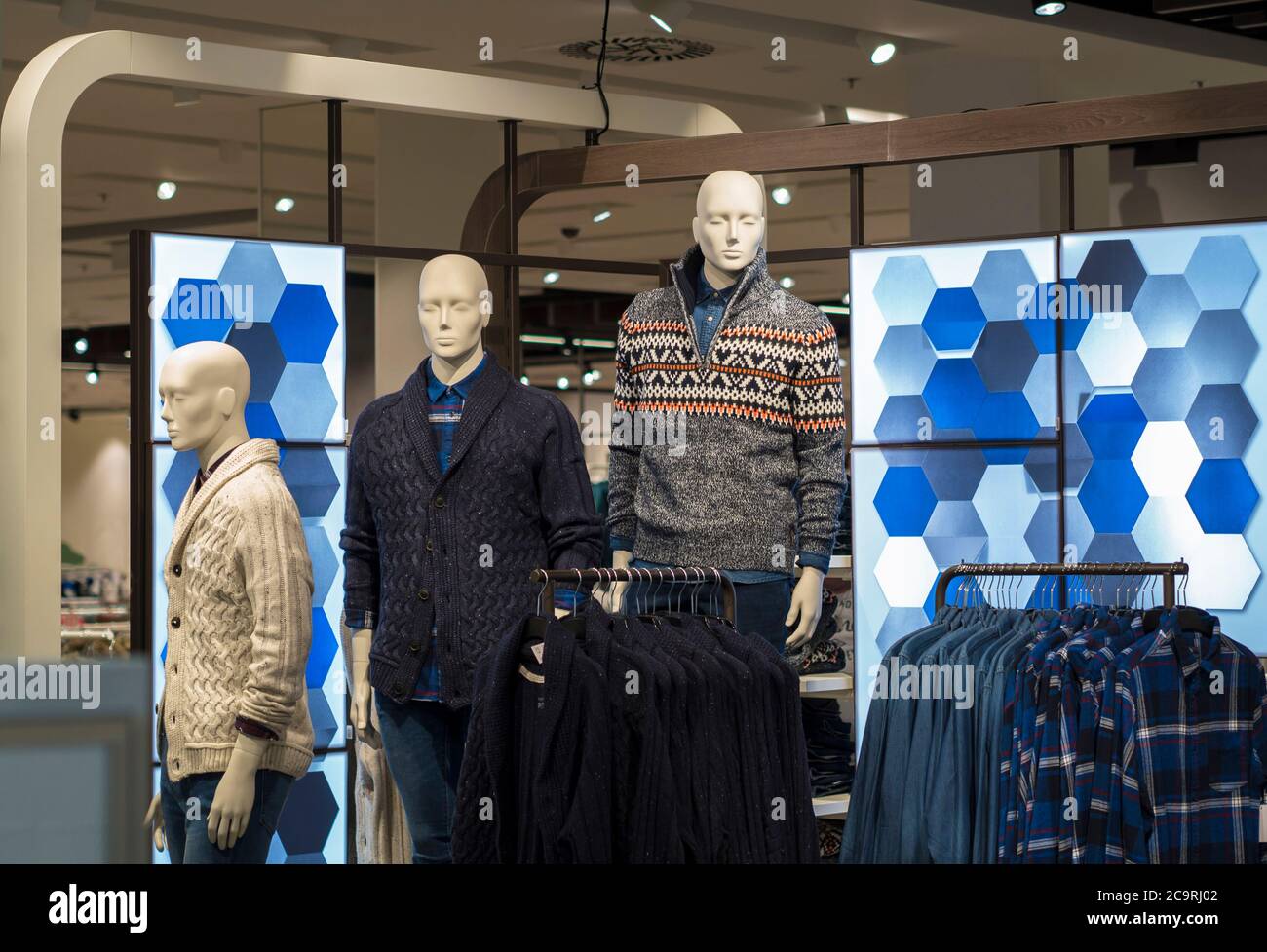 three men fashion figurine dressed in swaeter hangers with shirts and ...