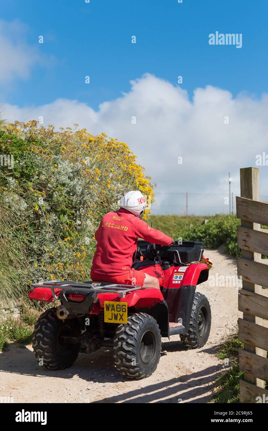 A RNLI Lifeguard riding a quad bike along the coastal path at Fistral ...
