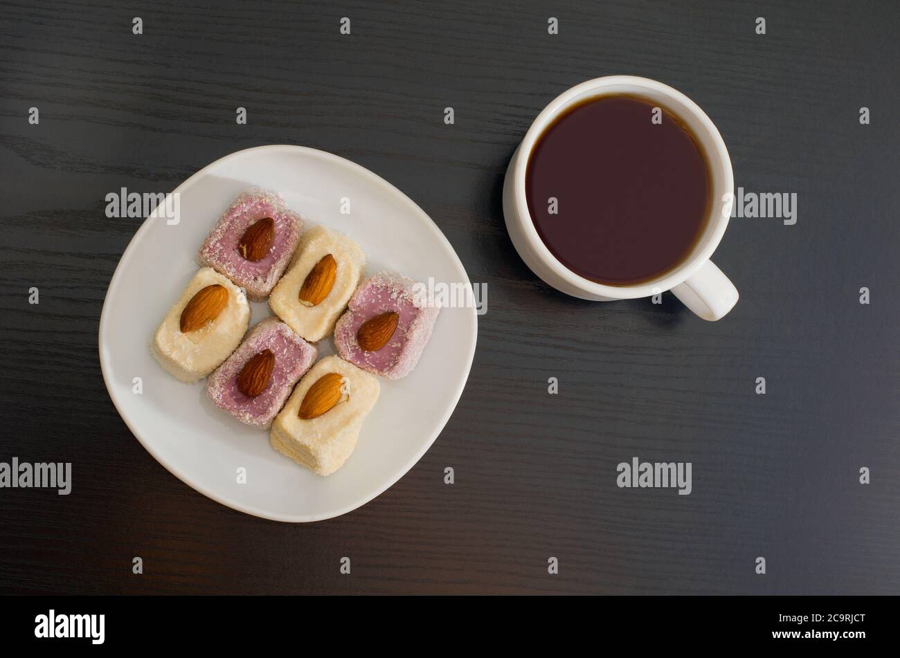 Mug of tea and Turkish Delight with almonds on a plate, top view, black ...