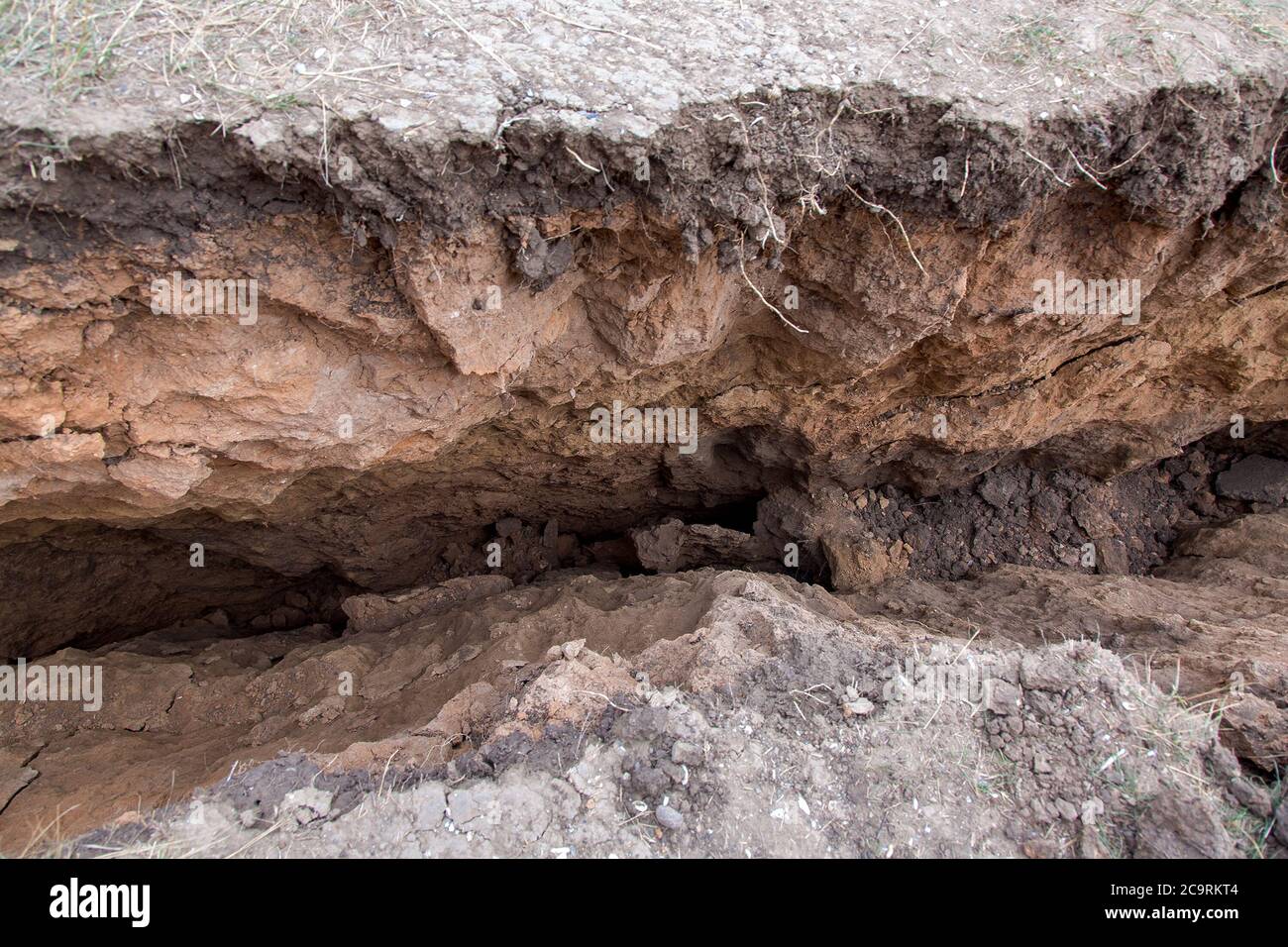 a landslide with cracks in the soil, a closeup of the crack inside the ...