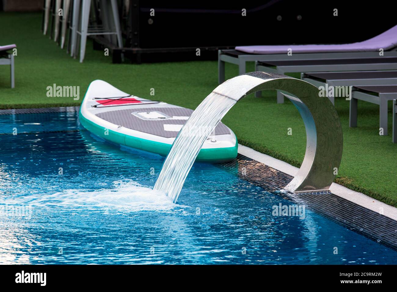 Fountain in the pool with a surfboard Stock Photo - Alamy