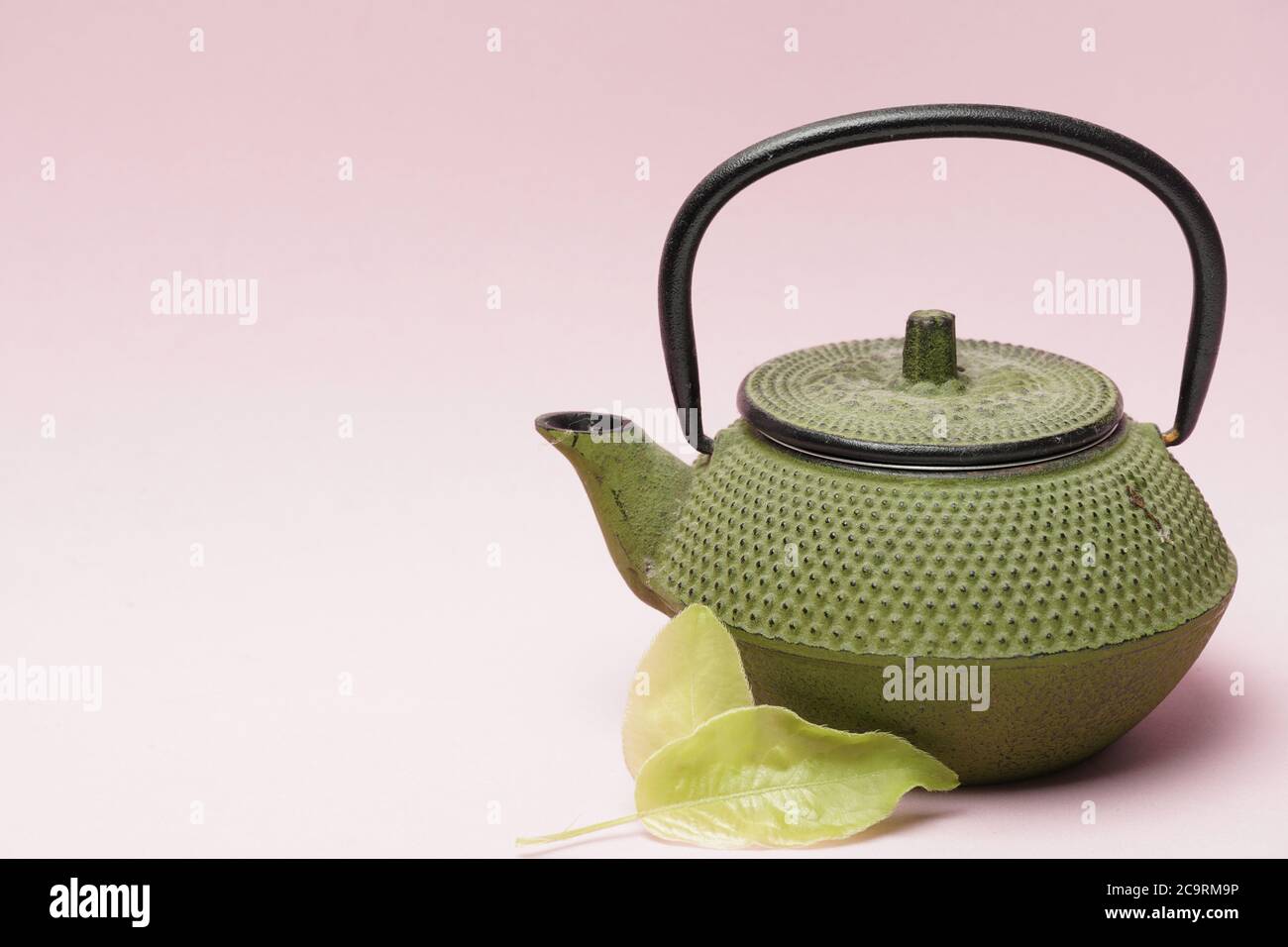 green teapot with green leaves and pink background Stock Photo - Alamy