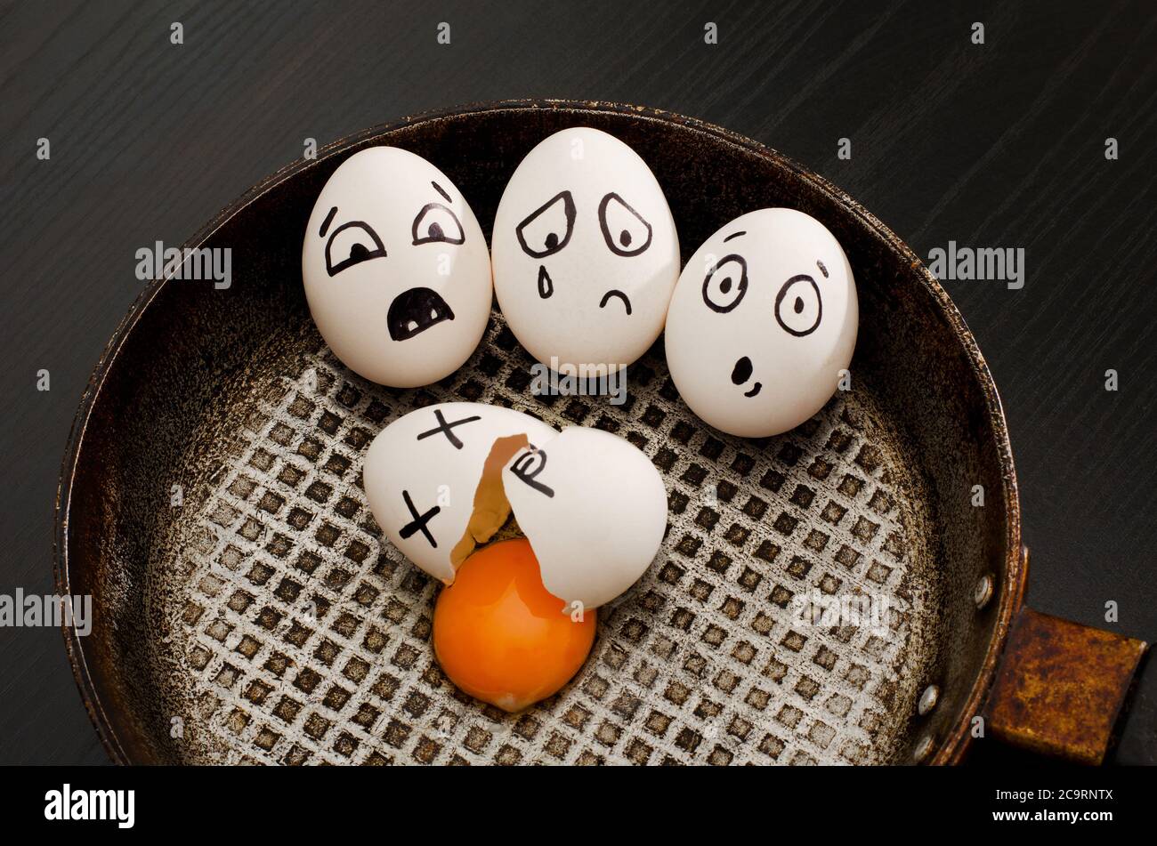 Top view of a broken egg, and egg with frightened faces in a frying pan ...