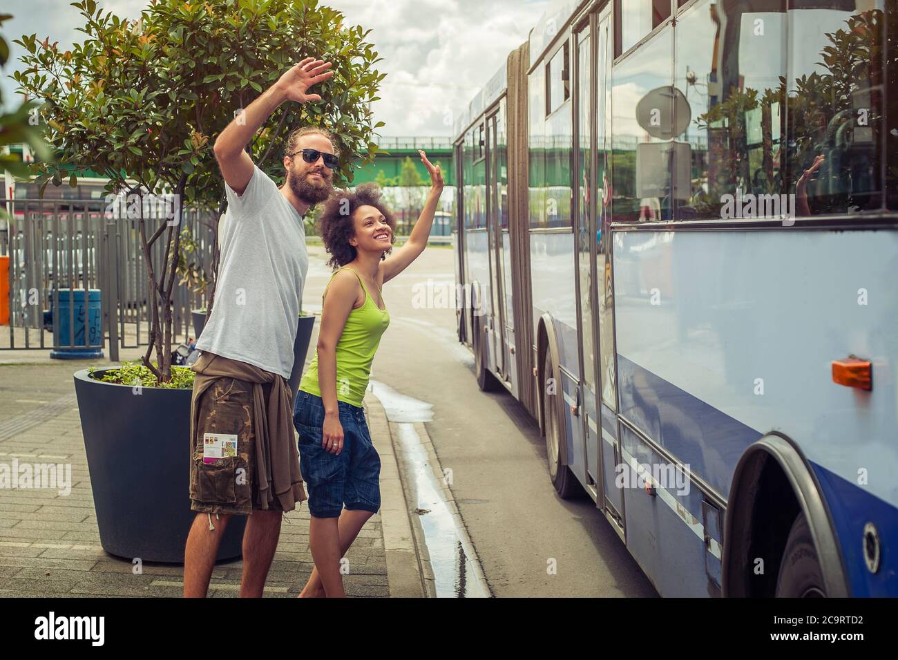 Young couple waving goodbye to their friends on the bus at bus station ...
