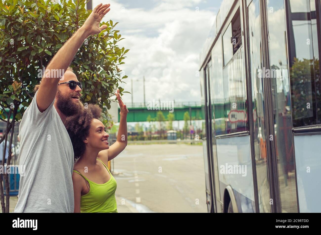 Young couple waving goodbye to their friends on the bus at bus station ...