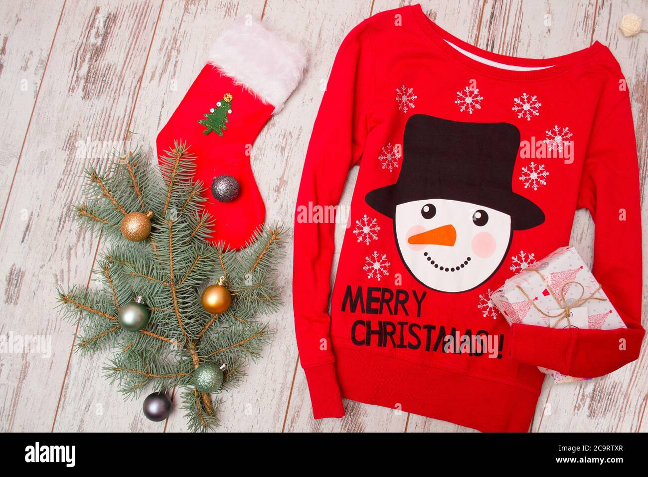 Red sweater with a snowman on a wooden background. Fur-tree branch with ...