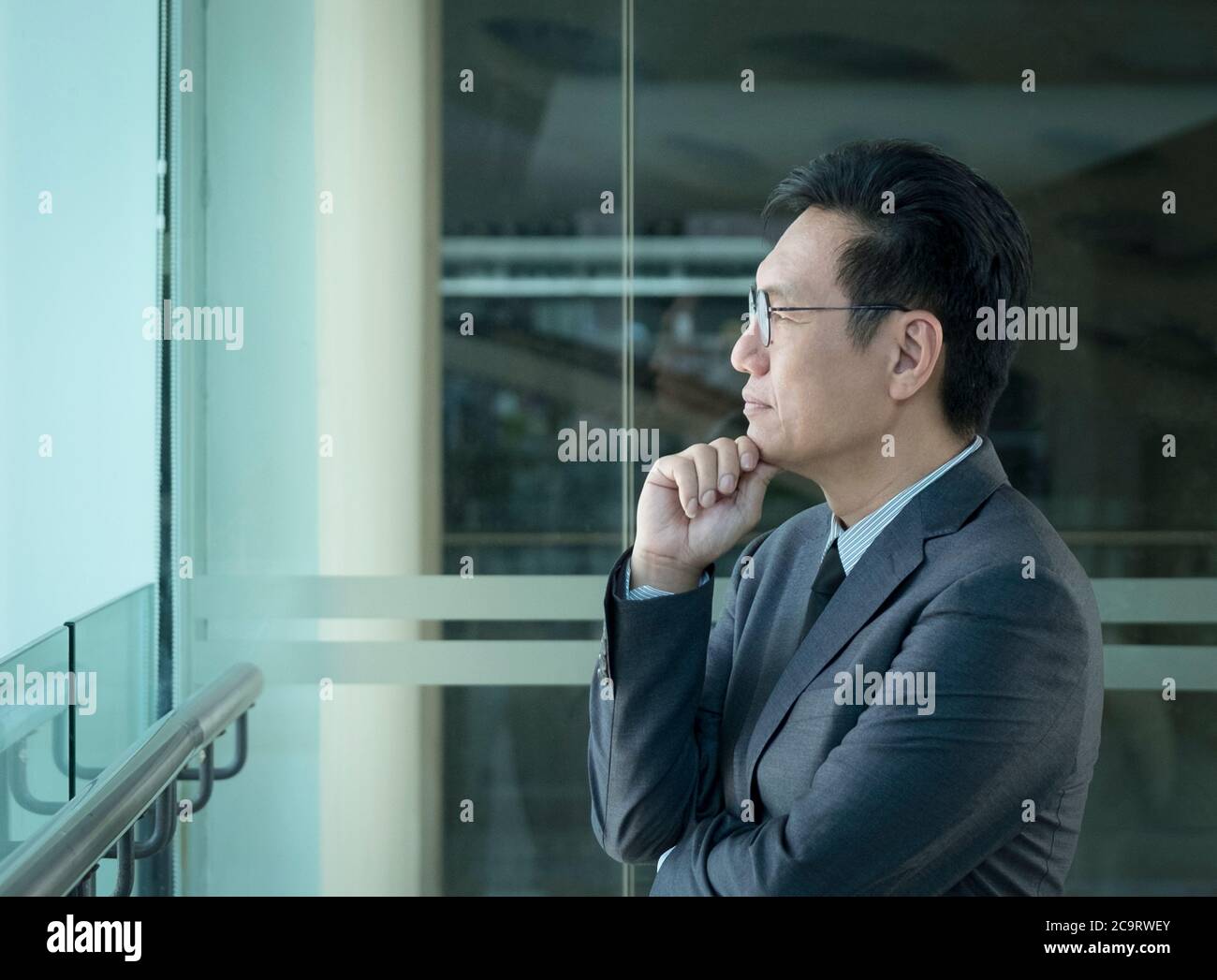 Portrait of a Chinese businessman in suit, thinking. Side view. Copy ...