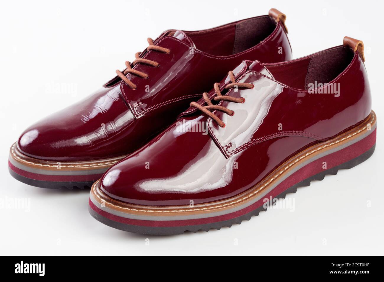Deep red shiny pair of shoes on a white background Stock Photo - Alamy