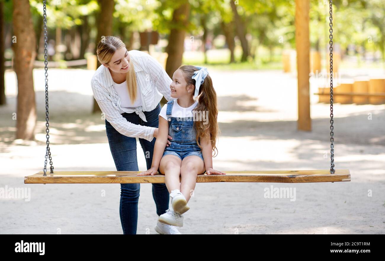 Mother Pushing Daughter On Swings Spending Time Together On Playground Stock Photo - Alamy