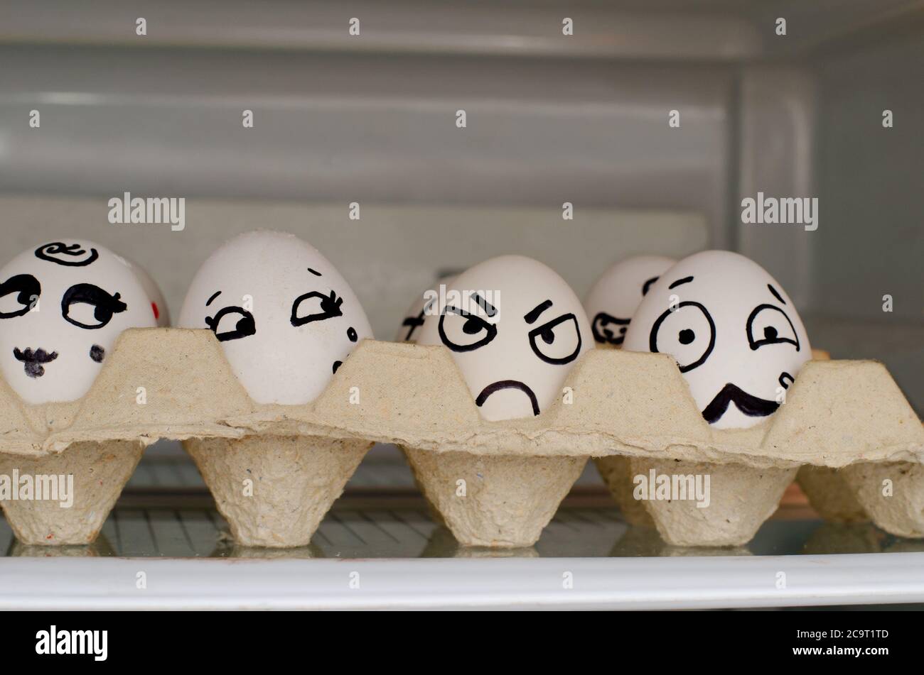 Eggs with painted emotions in a tray on a shelf in the refrigerator ...