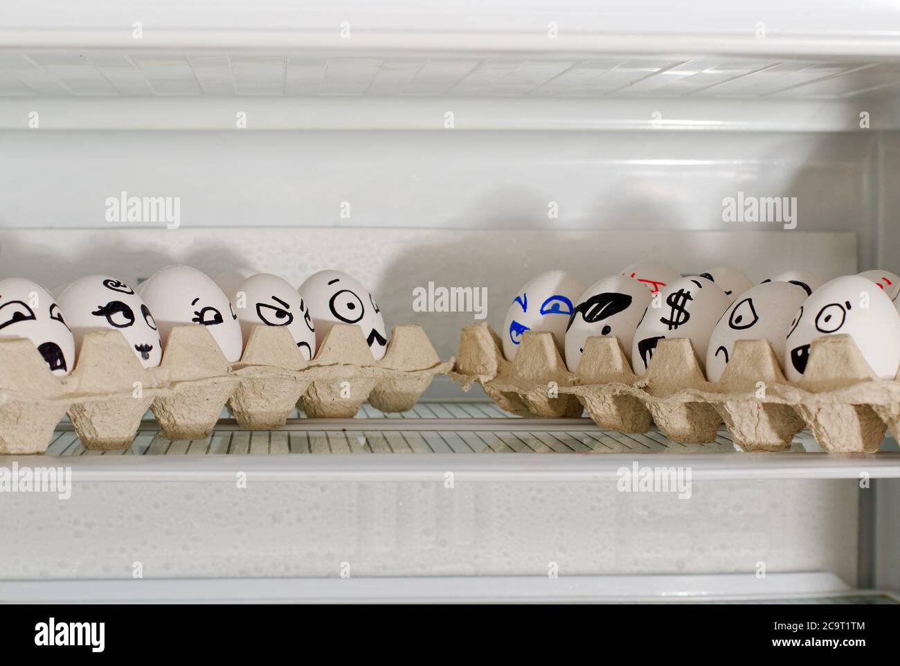 Two trays of eggs with smiles facing each other on a shelf in the ...