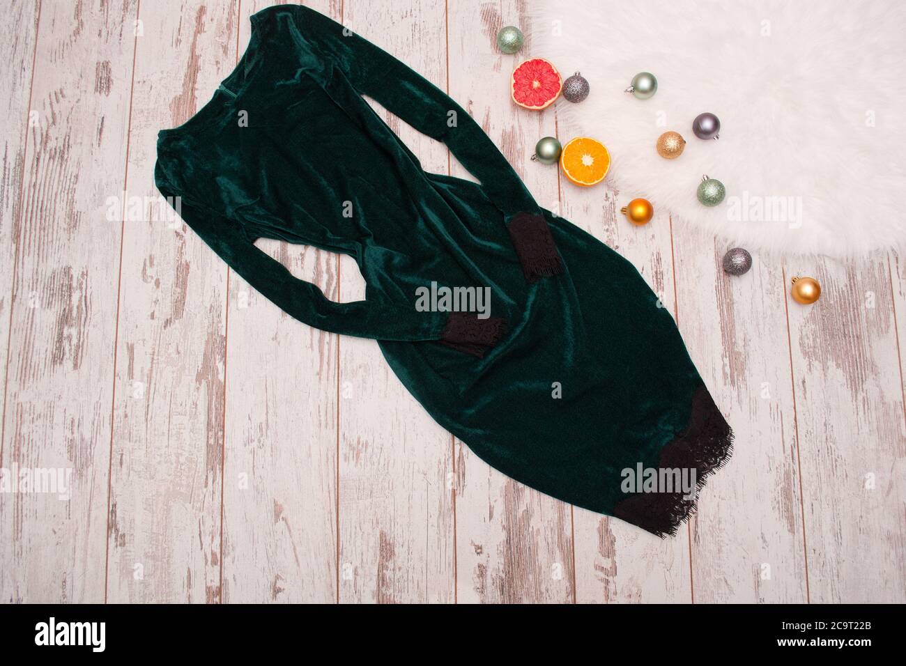 Emerald velvet dress on a wooden background, Christmas balls. Fashionable concept, top view ...