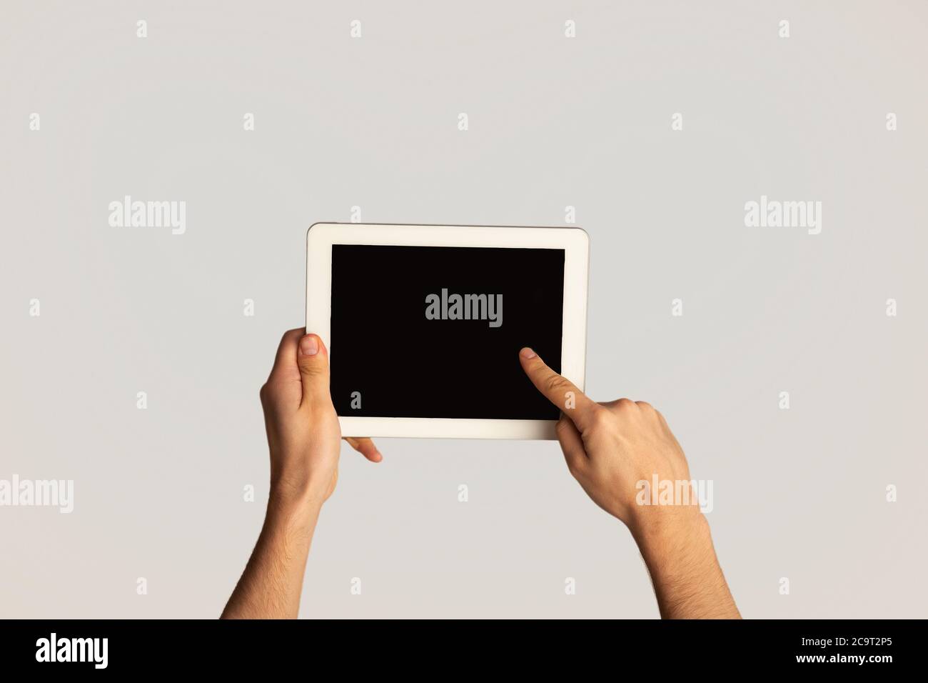 Unrecognizable man touching screen of modern tablet computer on light ...