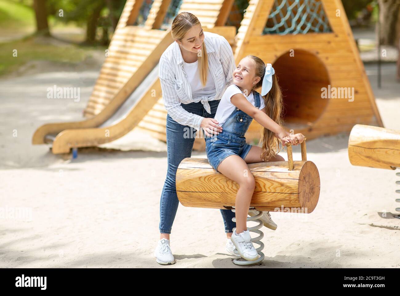 Mother Pushing Daughter On Swing Having Fun On Playground Outside Stock Photo - Alamy