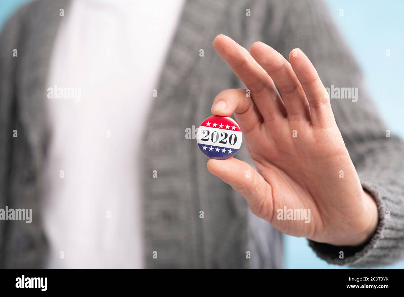 Incognito voter holding vote button on blue background Stock Photo - Alamy