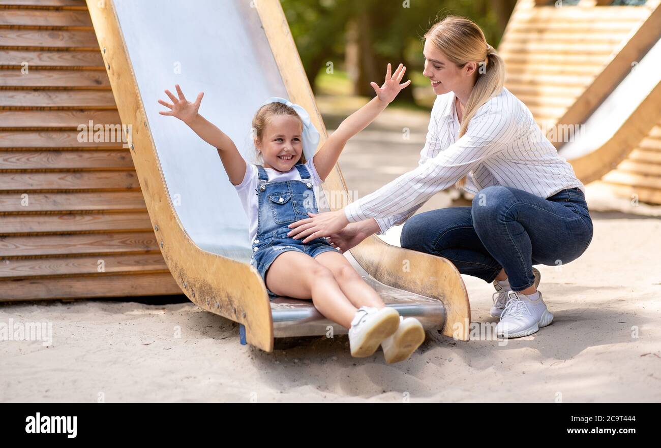 Girl Riding A Slide Having Fun With Mother On Playground Stock Photo ...