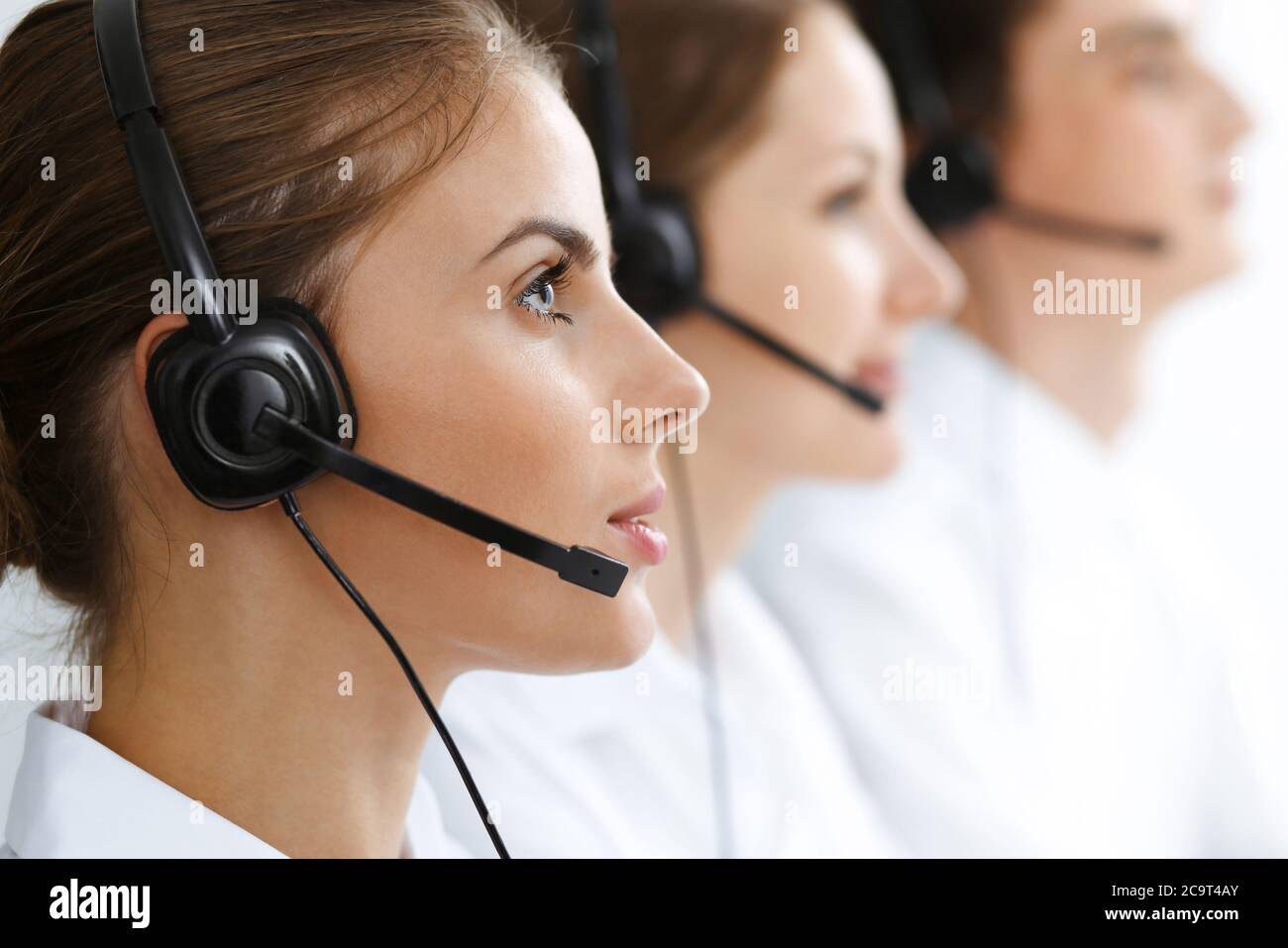Call center. Beautiful young woman using headset and computer to help ...