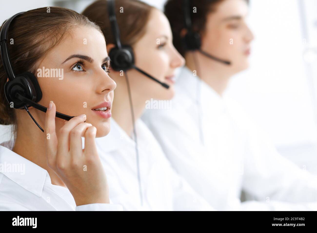 Call center. Beautiful young woman using headset and computer to help ...