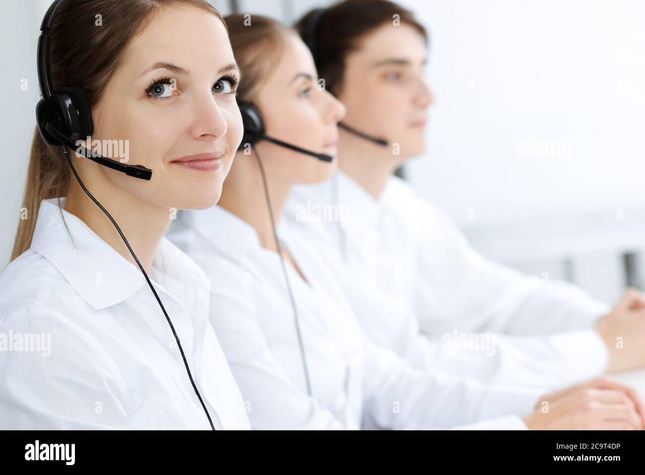 Call center. Beautiful young woman using headset and computer to help ...
