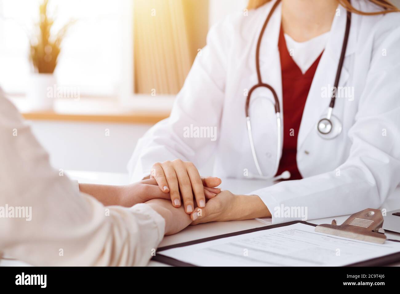 Hands of unknown woman-doctor reassuring her female patient in sunny ...