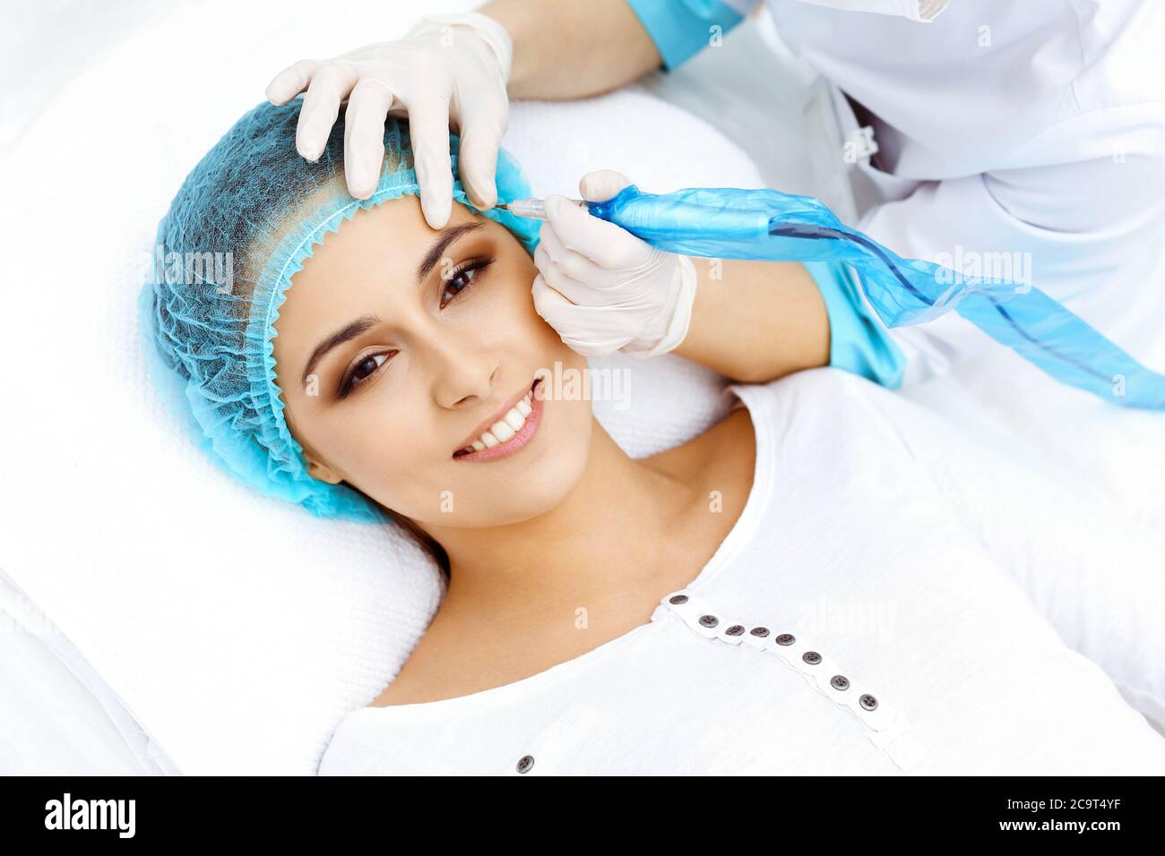 Professional beautician doing eyebrow tattoo at woman face. Permanent ...