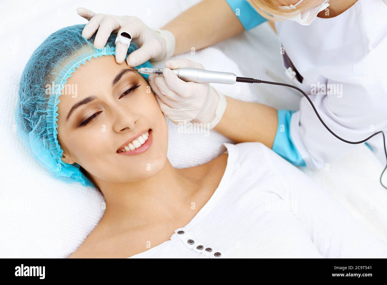 Professional beautician doing eyebrow tattoo at woman face. Permanent ...