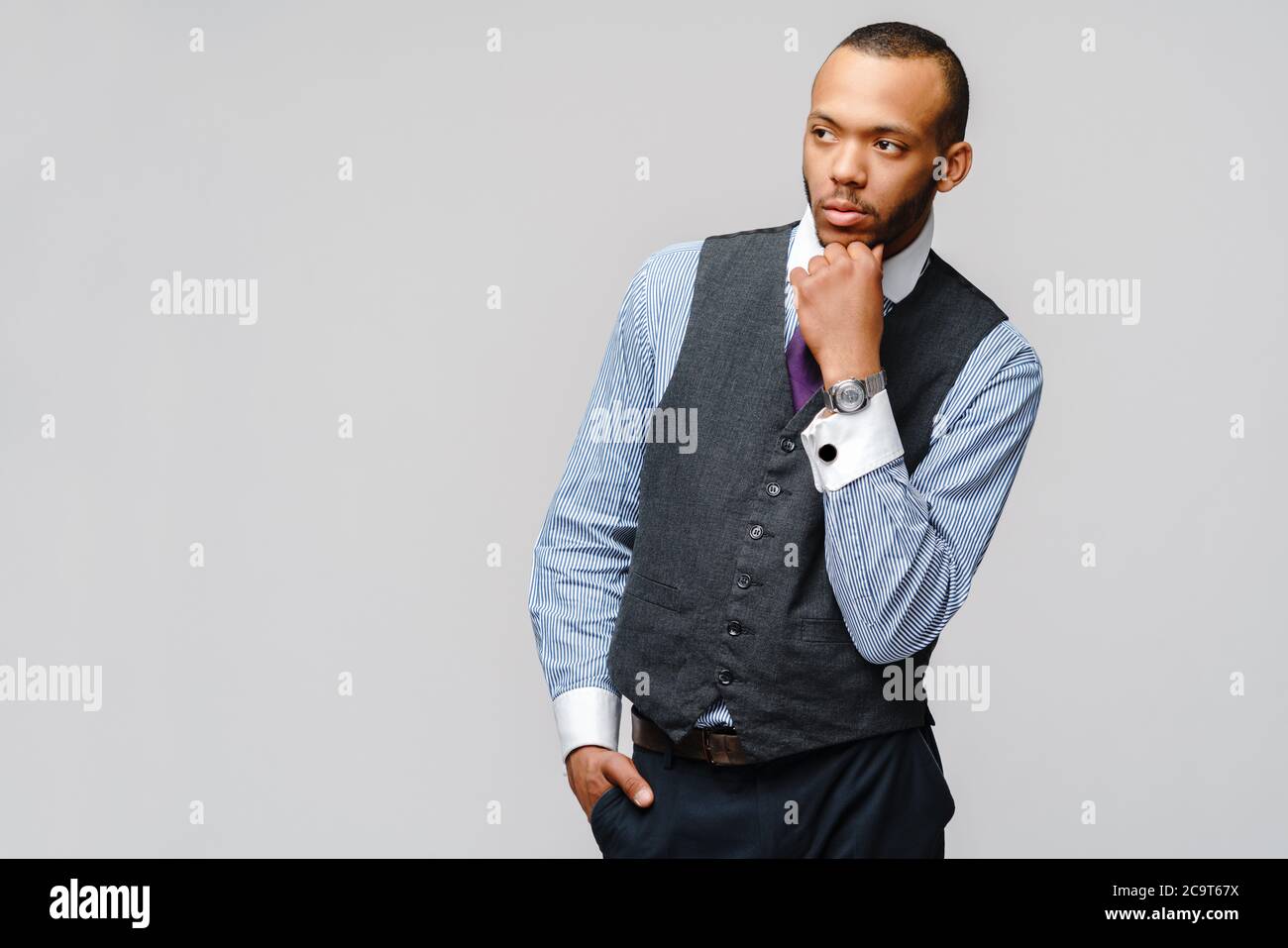 Studio shot of young African-American businessmanman over grey ...