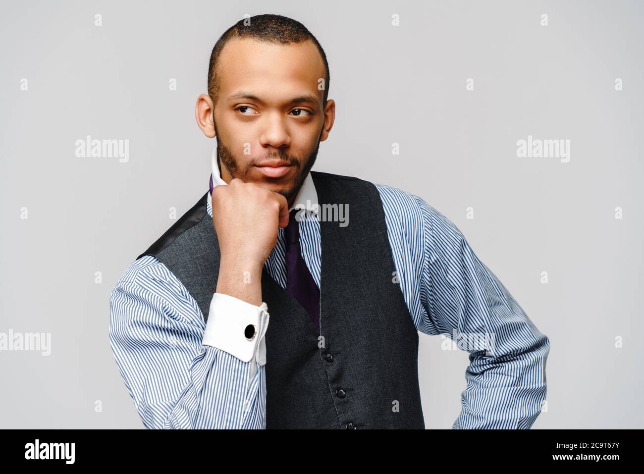 Studio shot of young African-American businessmanman over grey ...