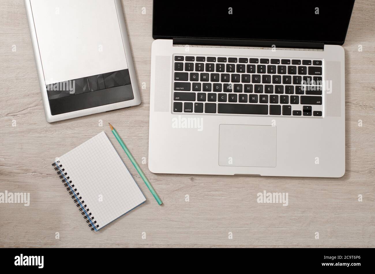 Open the laptop, graphics tablet and notebook with pencil on a light ...
