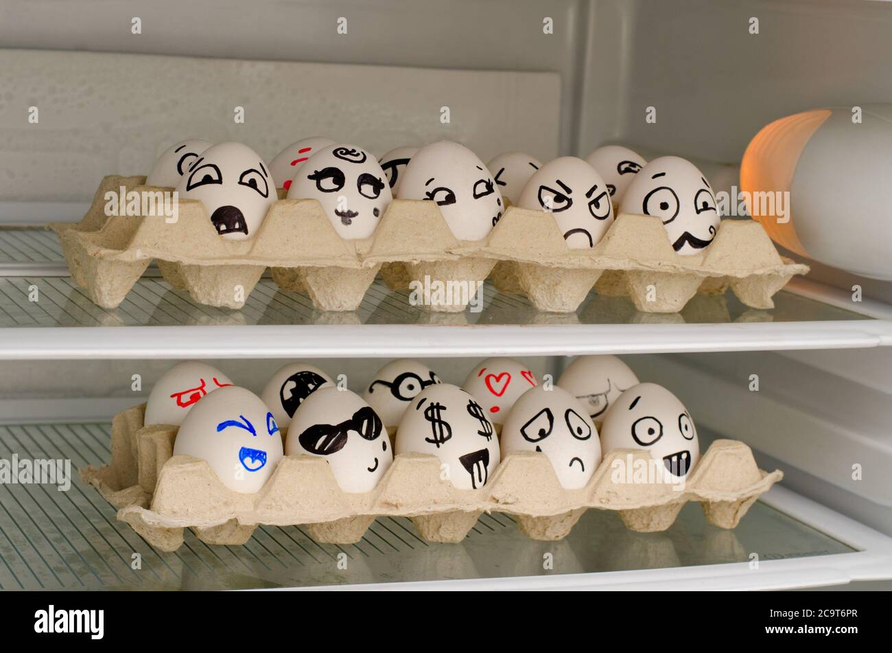Two trays with painted smiles on the eggs on the refrigerator shelves ...
