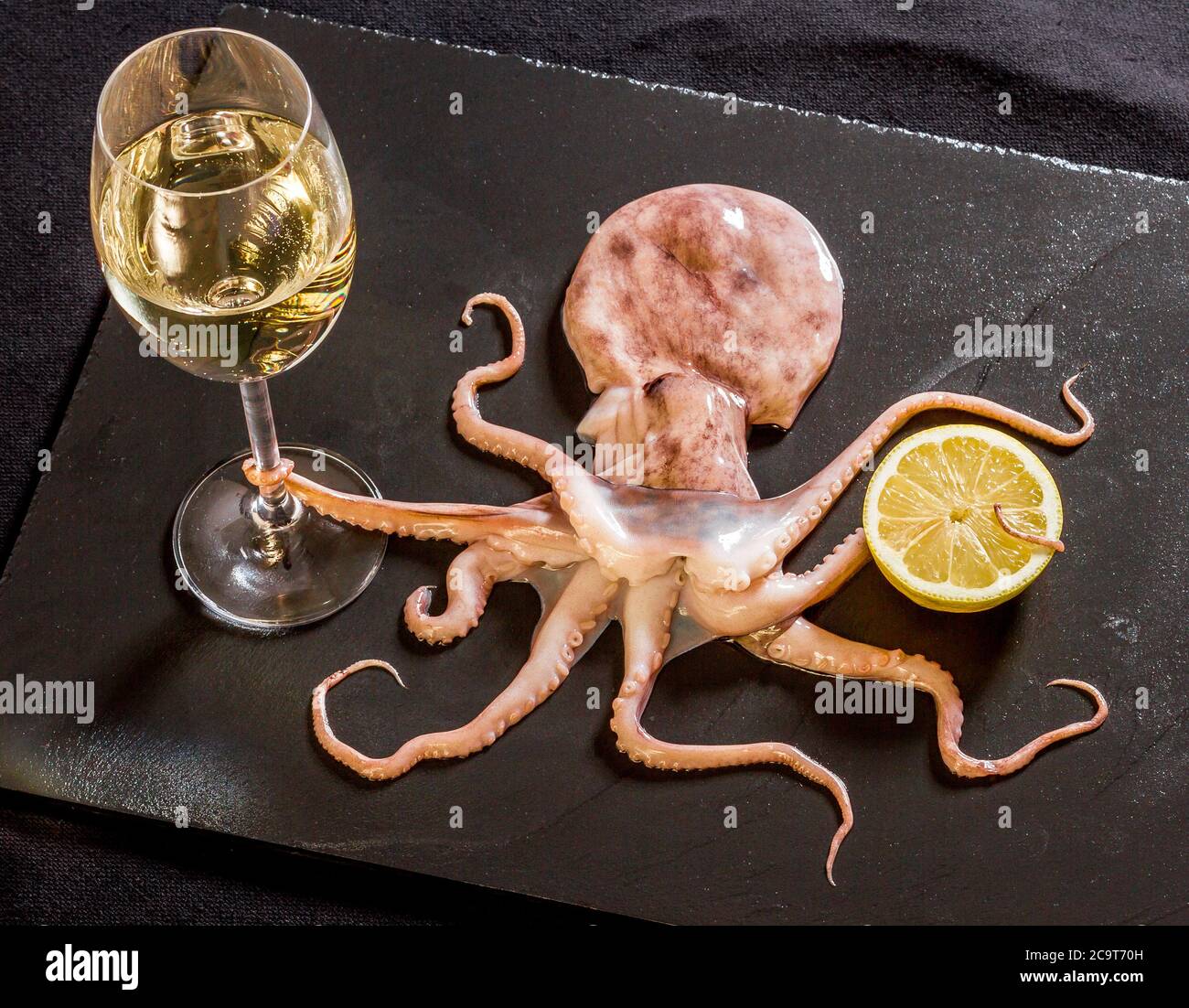 Octopus hold wine, on black slate, top view Stock Photo - Alamy