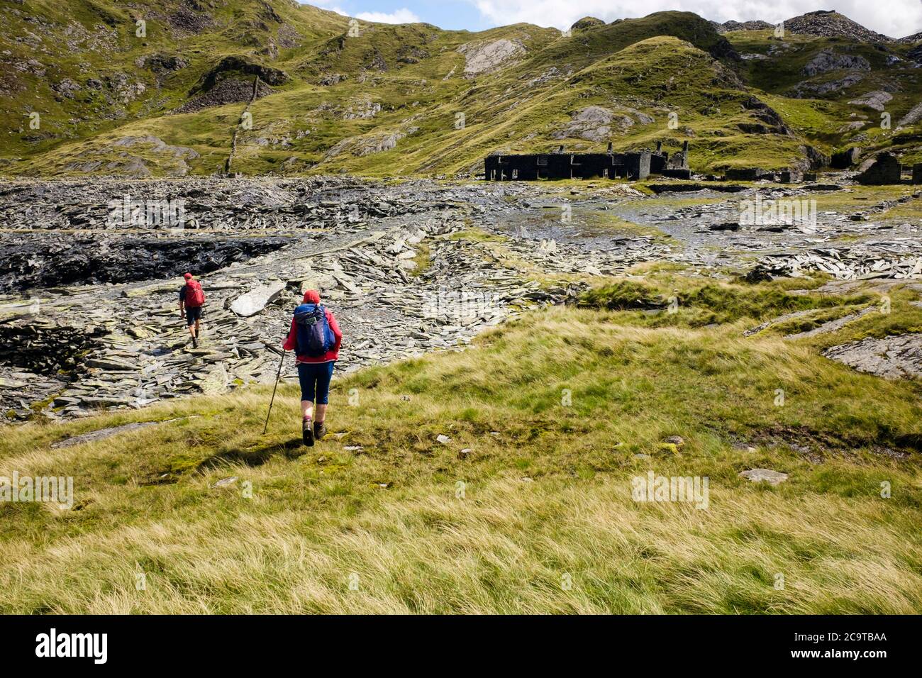 Hikers hiking to old ruins of Rhosydd slate quarry quarrymen's barracks from Cnicht in Snowdonia ...