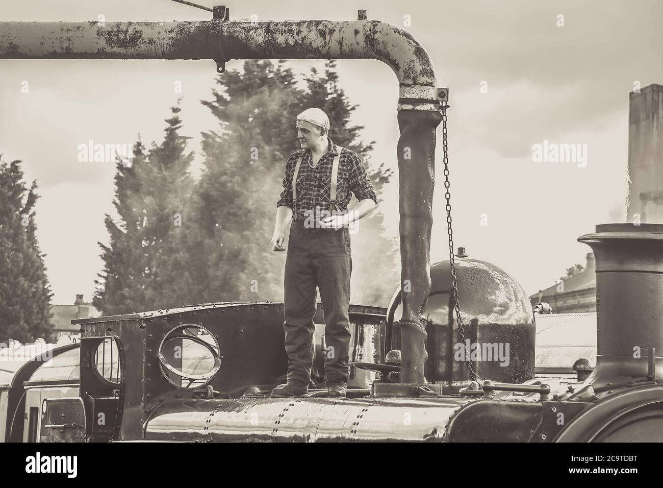 Monochrome engine crew fireman filling water tank of vintage steam ...