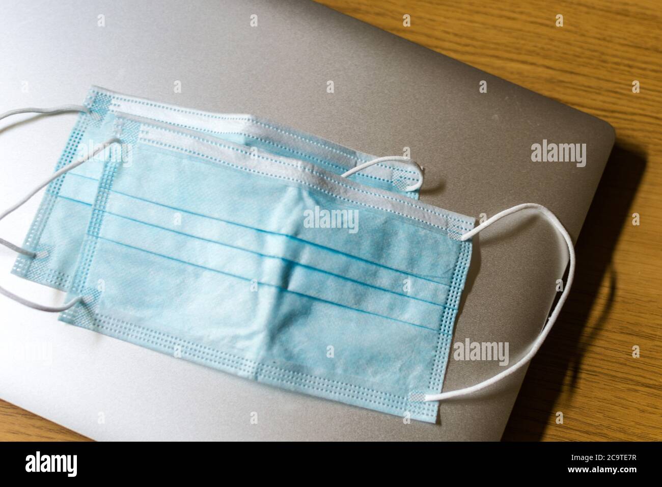 Two surgical face mask placed on top of laptop to illustrate face ...