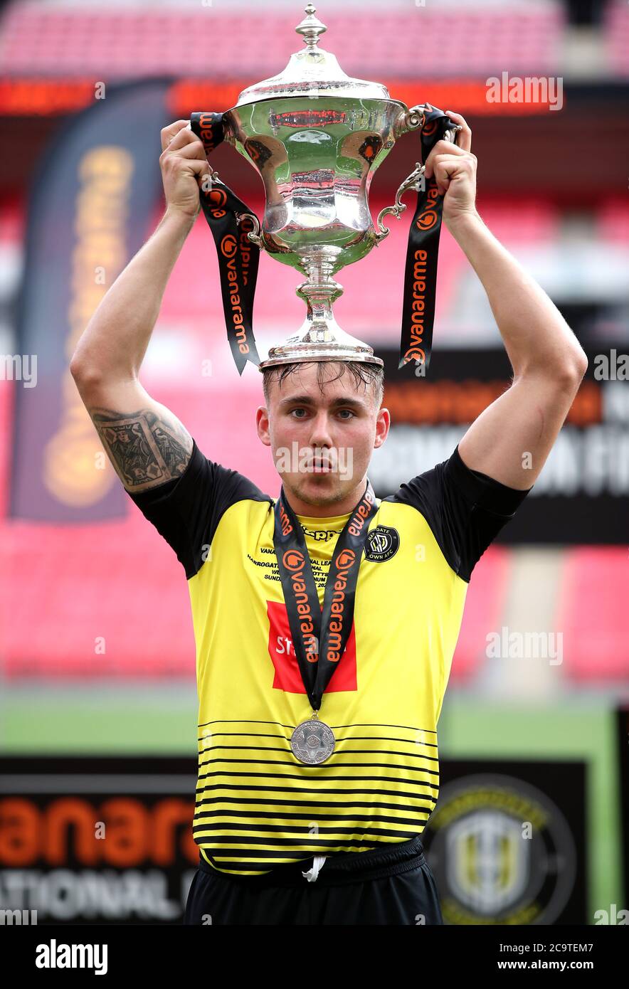 Harrogate Town's Jack Diamond lifts the trophy after the final whistle ...