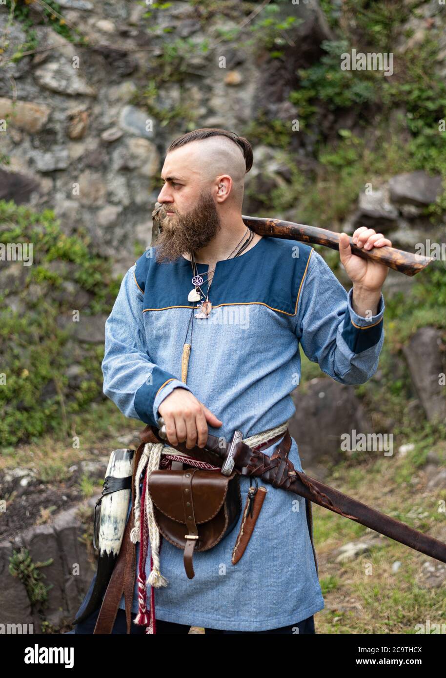 A man in medieval clothes wields an ax in the ruins of an ancient ...