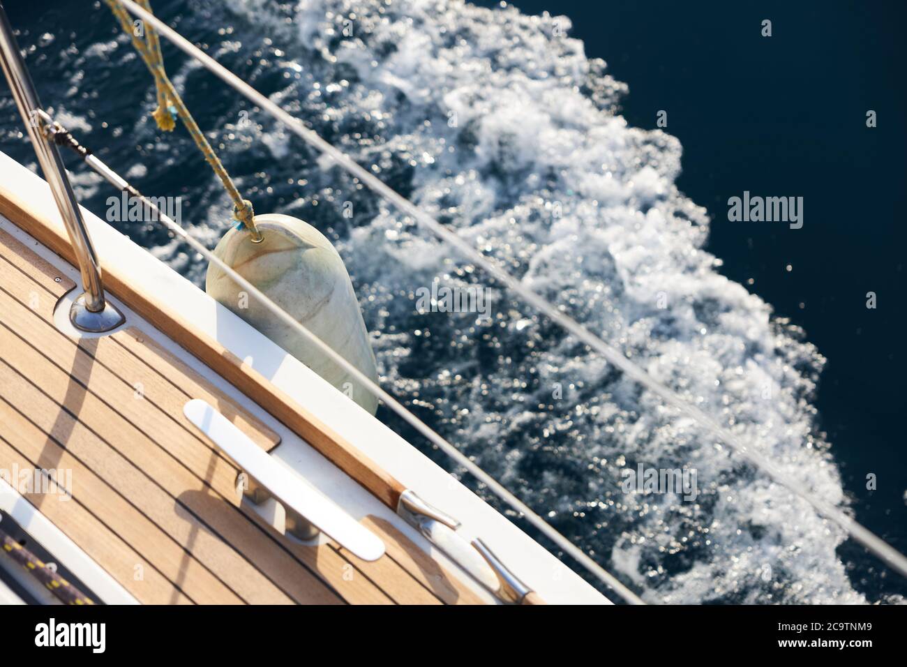 View of the teak deck of a sailing yacht moving on a calm surface of ...
